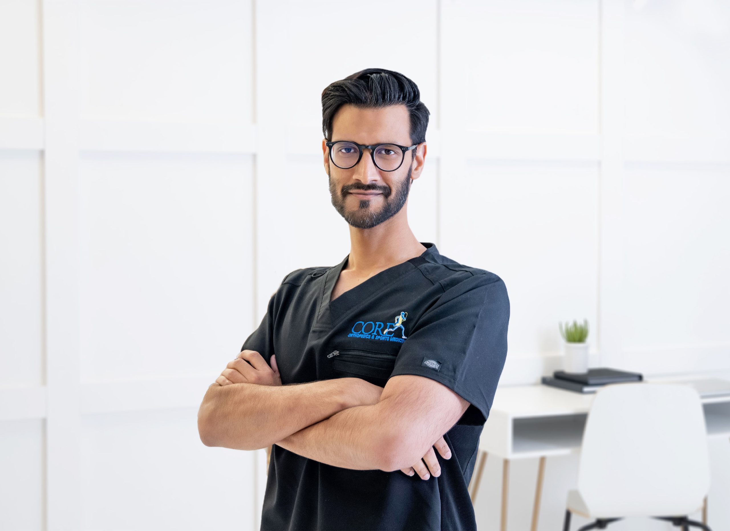 Dr Baig Black Scrubs white desk background - CORE Orthopedics